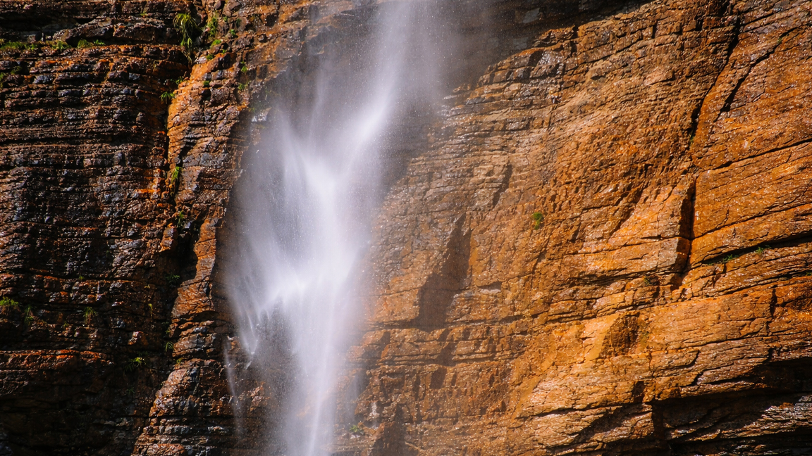 Cascata natural em penhasco de rocha texturizada sob luz quente