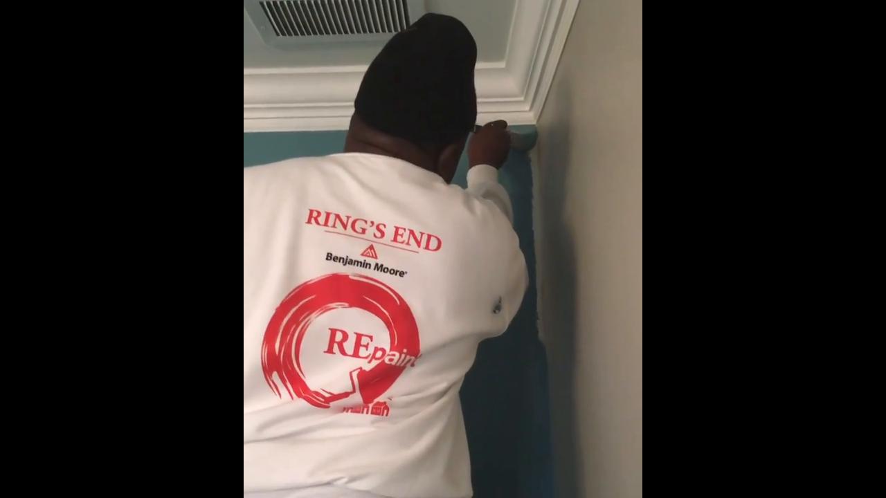 Painting clean wall edge with blue and beige contrast creating smooth ...