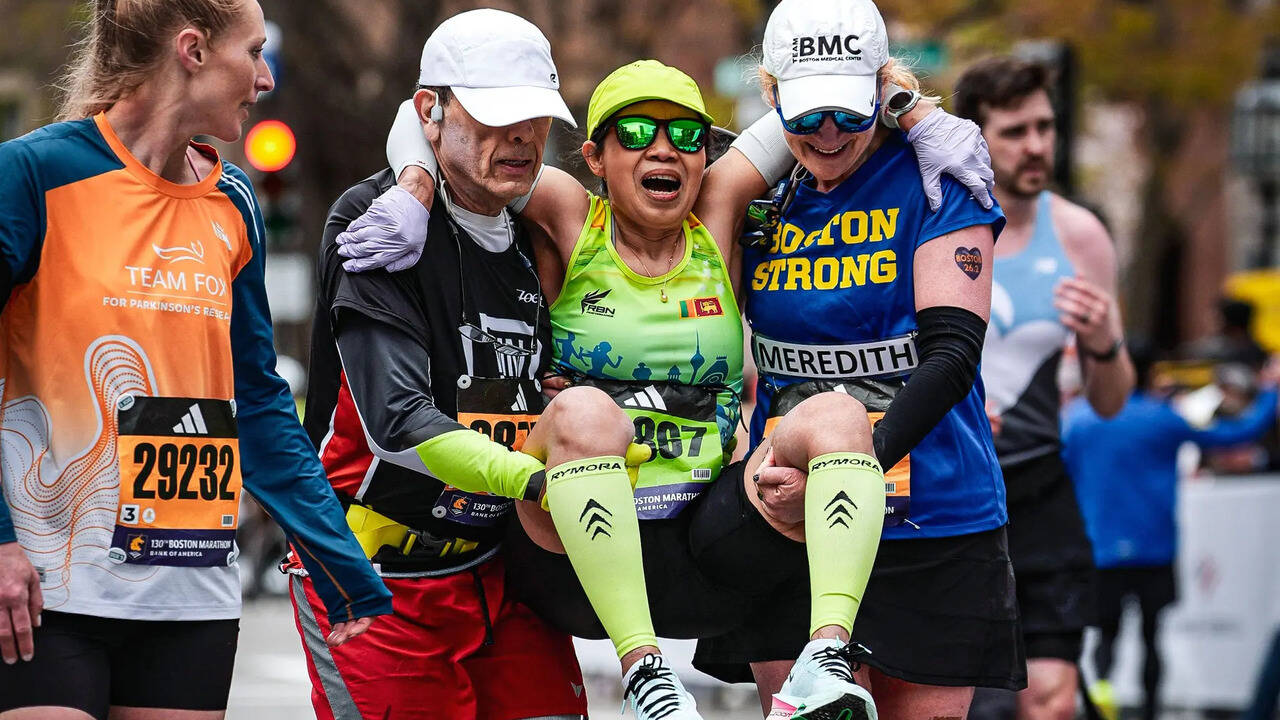 Runners assist each other at Boston Marathon finish line