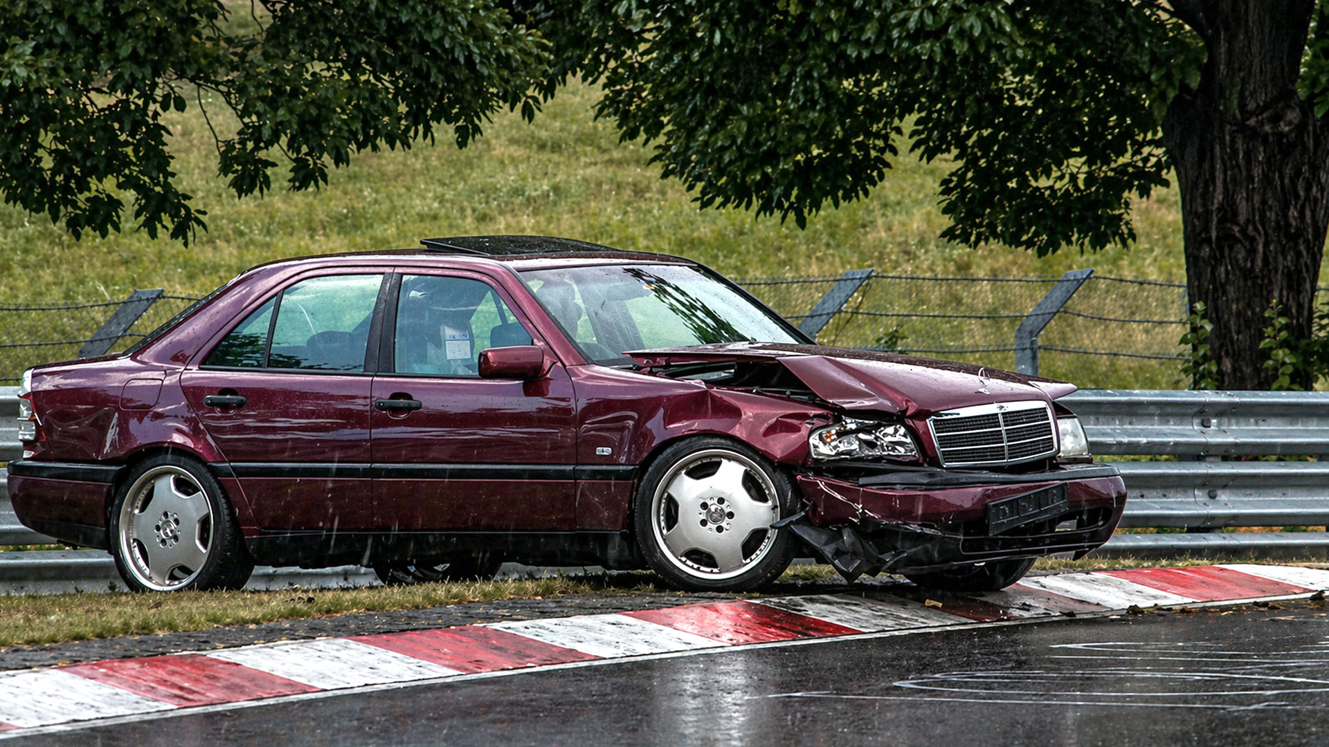Old Mercedes crashes into barrier after losing control on wet track
