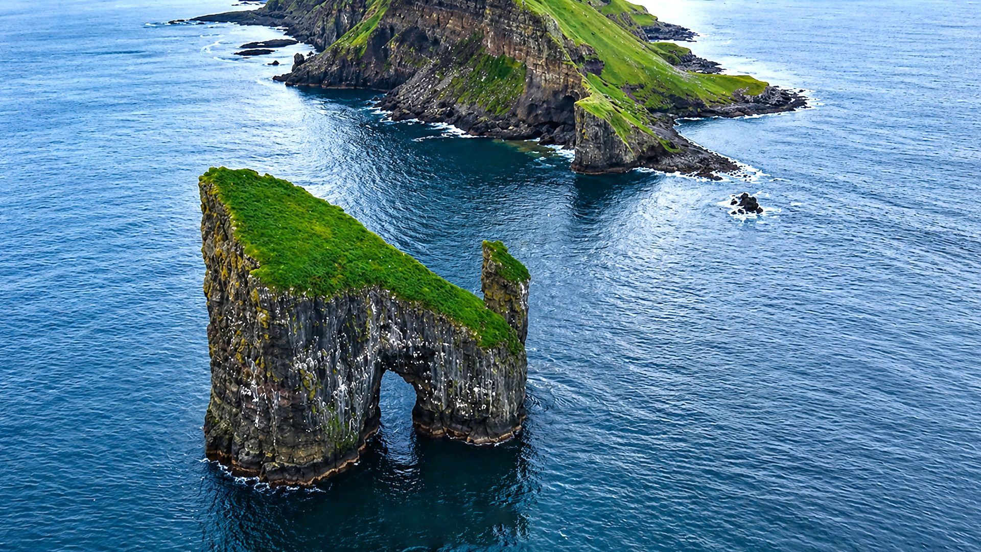 A natural sea arch rising from the ocean in the Faroe Islands