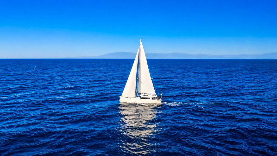 Zeilboot vaart over diepe blauwe oceaan onder heldere lucht