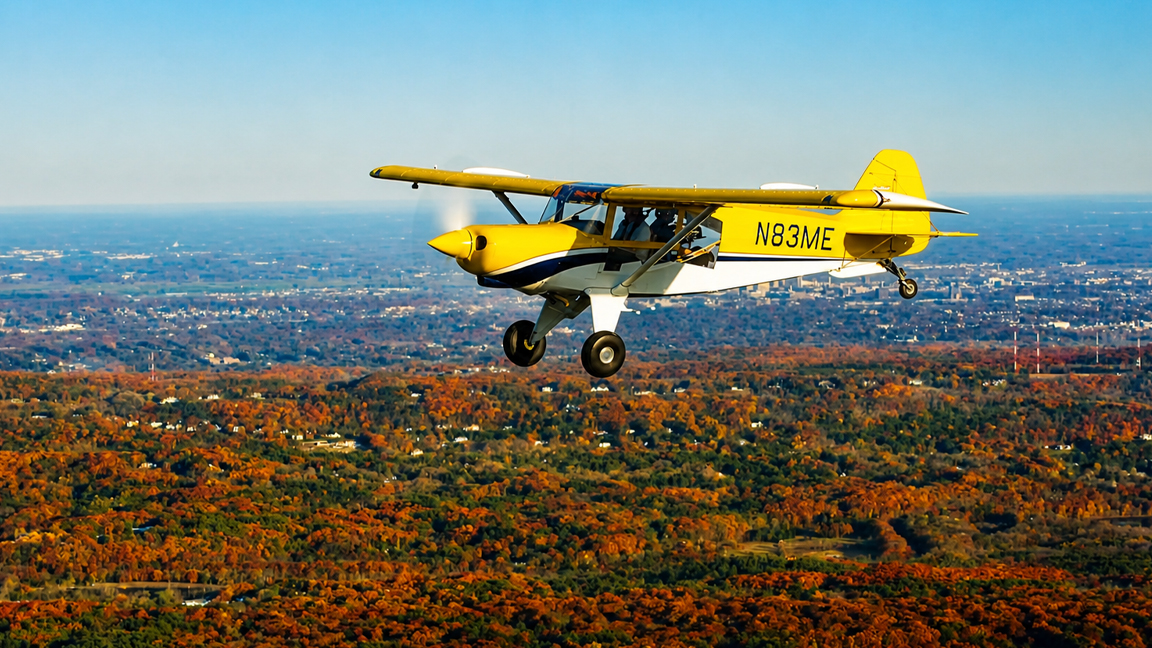 Yellow light aircraft flying over autumn landscape
