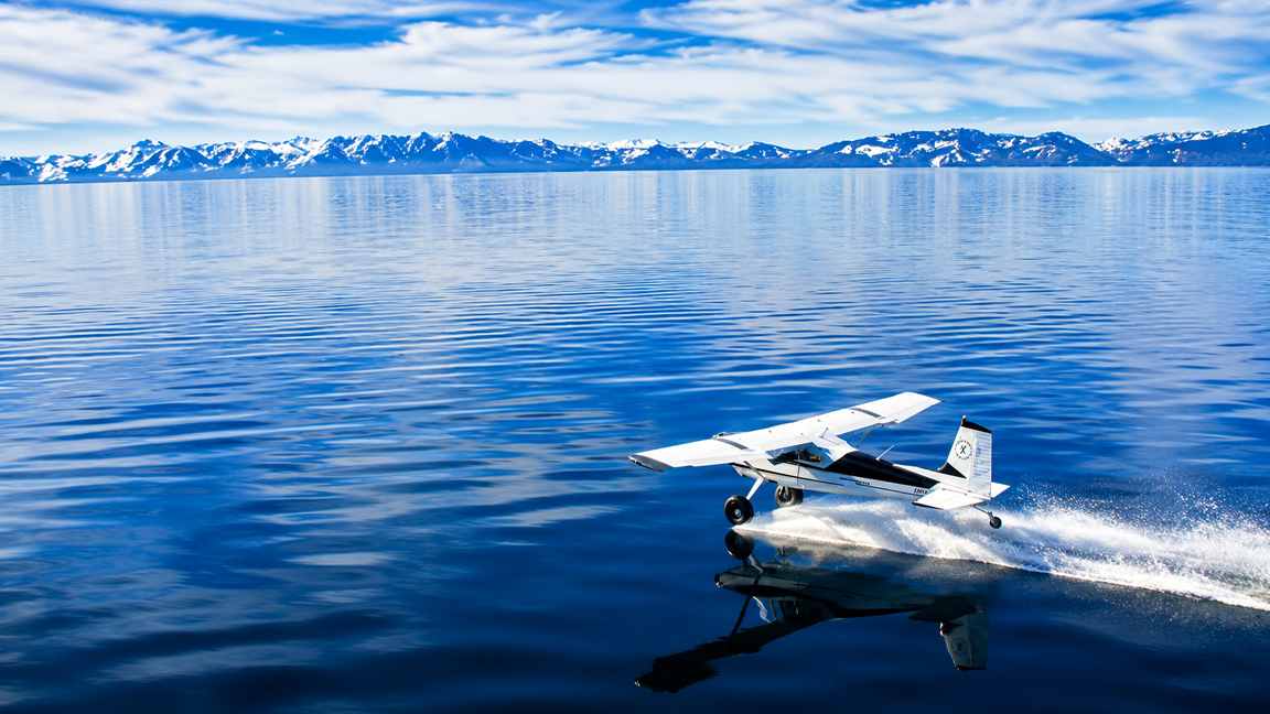 Light aircraft splashing across calm sea under blue sky