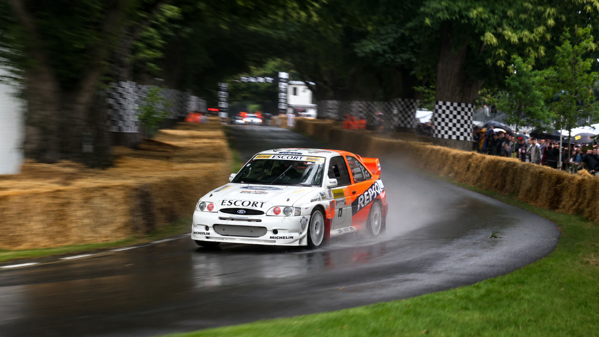 A vintage Ford rally car almost spins on slippery circuit