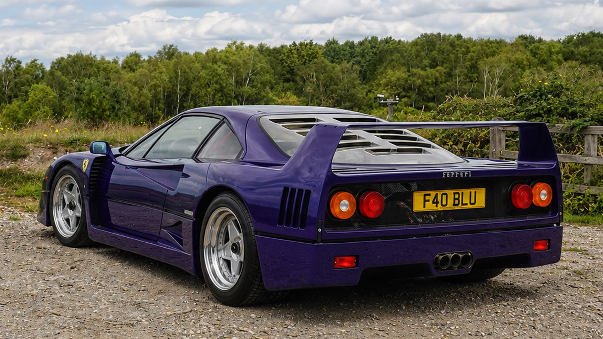 Purple Ferrari F40 parked in scenic countryside location