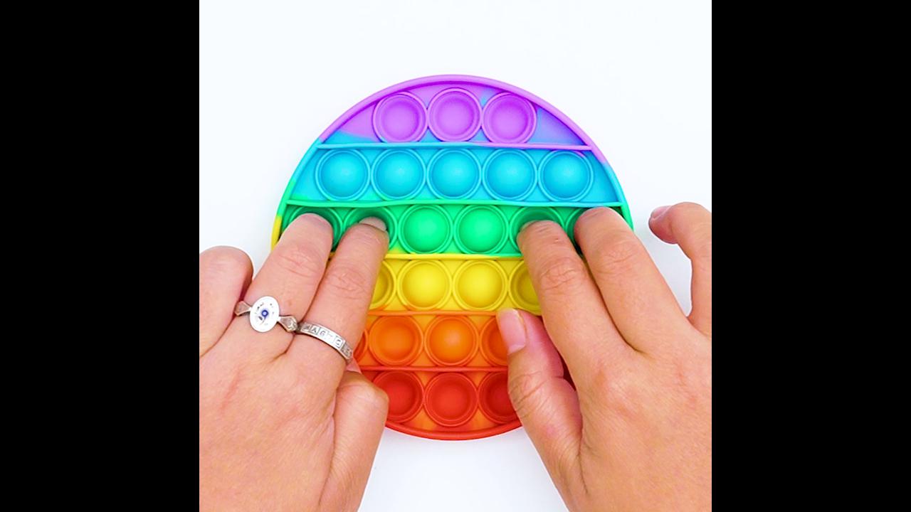 Playing with a colorful round pop it in bright rainbow layers