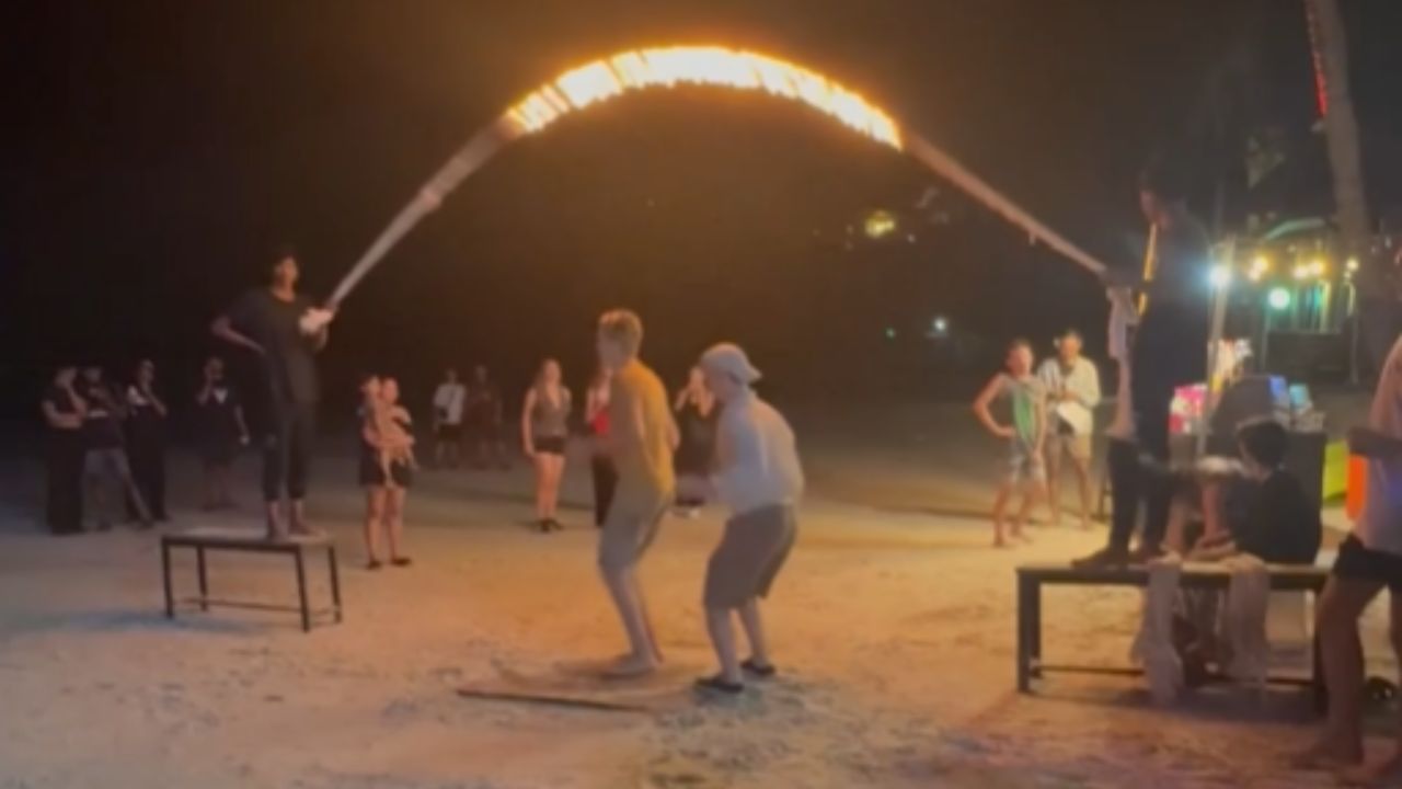 Two boys dare to jump a rope with flames burning in the center