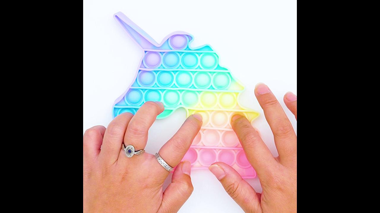 Playing with a colorful unicorn pop it in soft pastel gradient