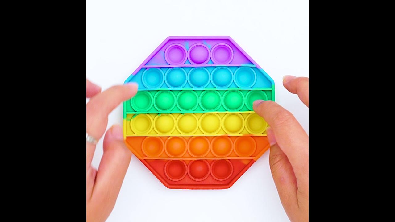 Playing with a colorful house shaped pop it in bright rainbow layers