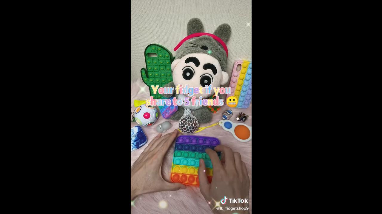 Pressing green and rainbow pop it toys beside a soft panda doll
