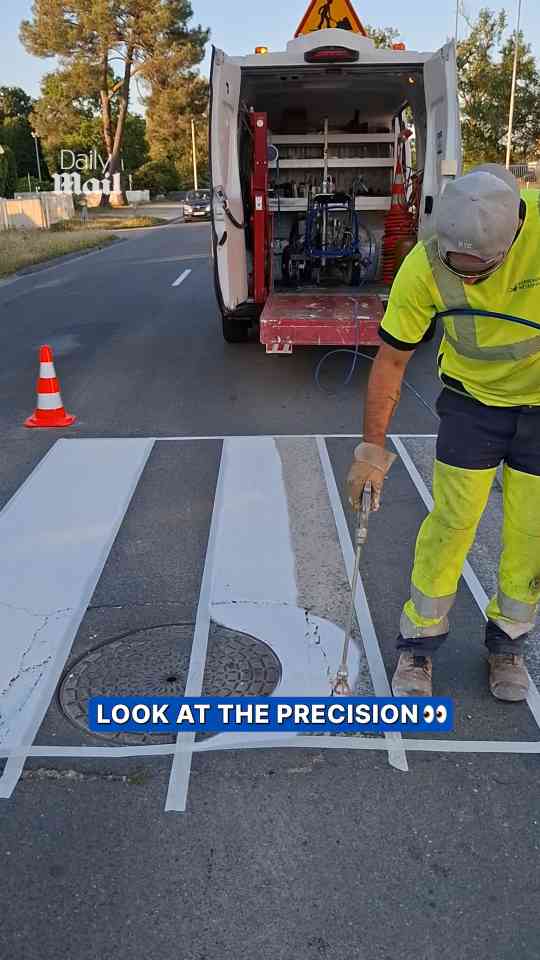 Worker paints zebra crossing with precise, steady technique