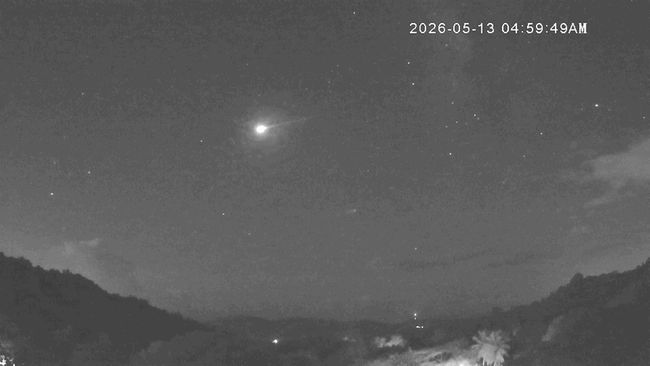Bright meteor creates lens flare as it streaks across night sky