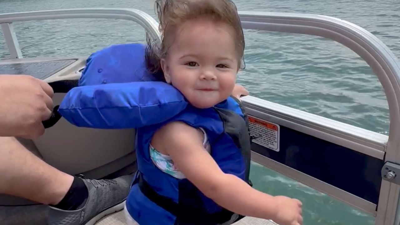 Toddler stands on a moving boat as wind blows her face