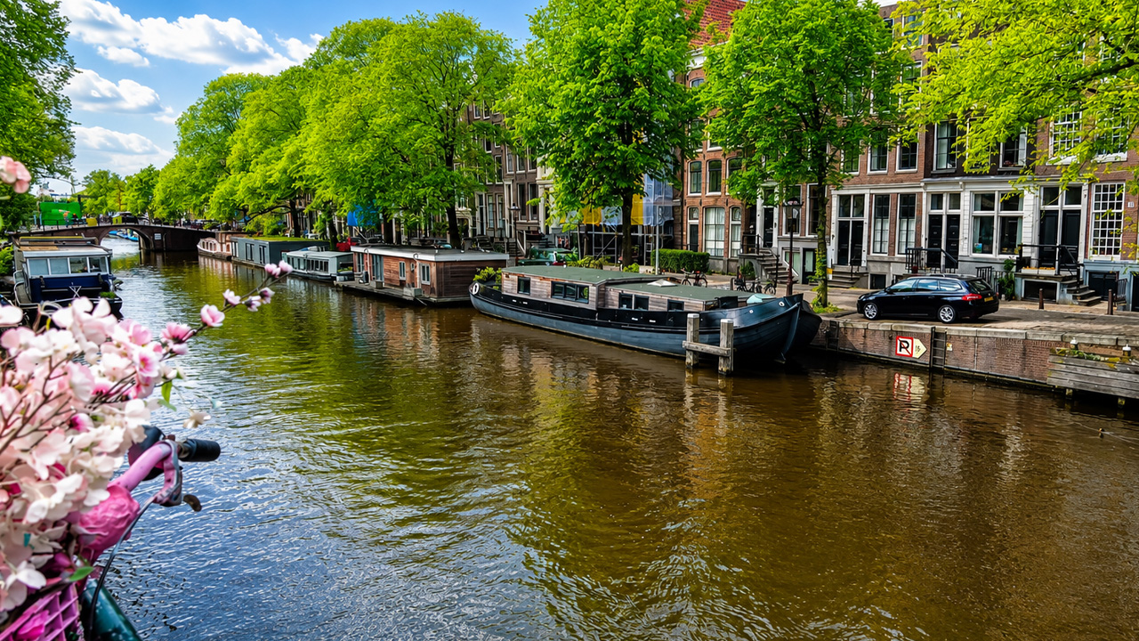 Amsterdam canal walk with houseboats and spring views