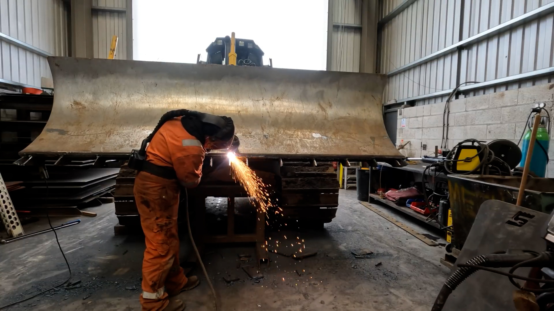 Heavy equipment blade welding inside fabrication workshop