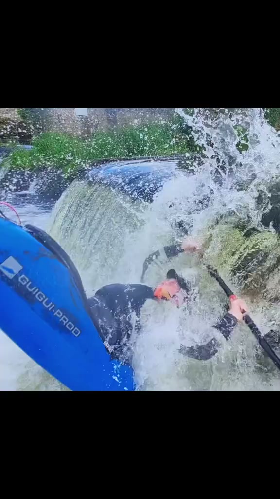 Sideways kayak slide over weir ends in freestyle splash