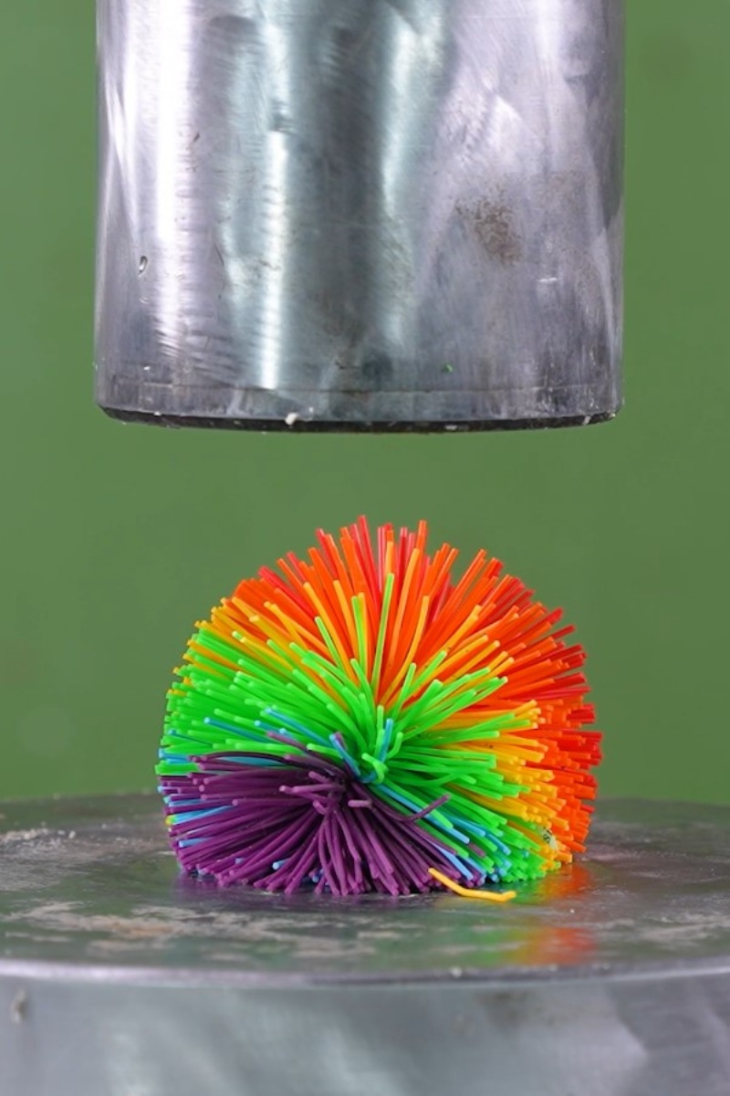 Crushing a colorful toy under hydraulic pressure
