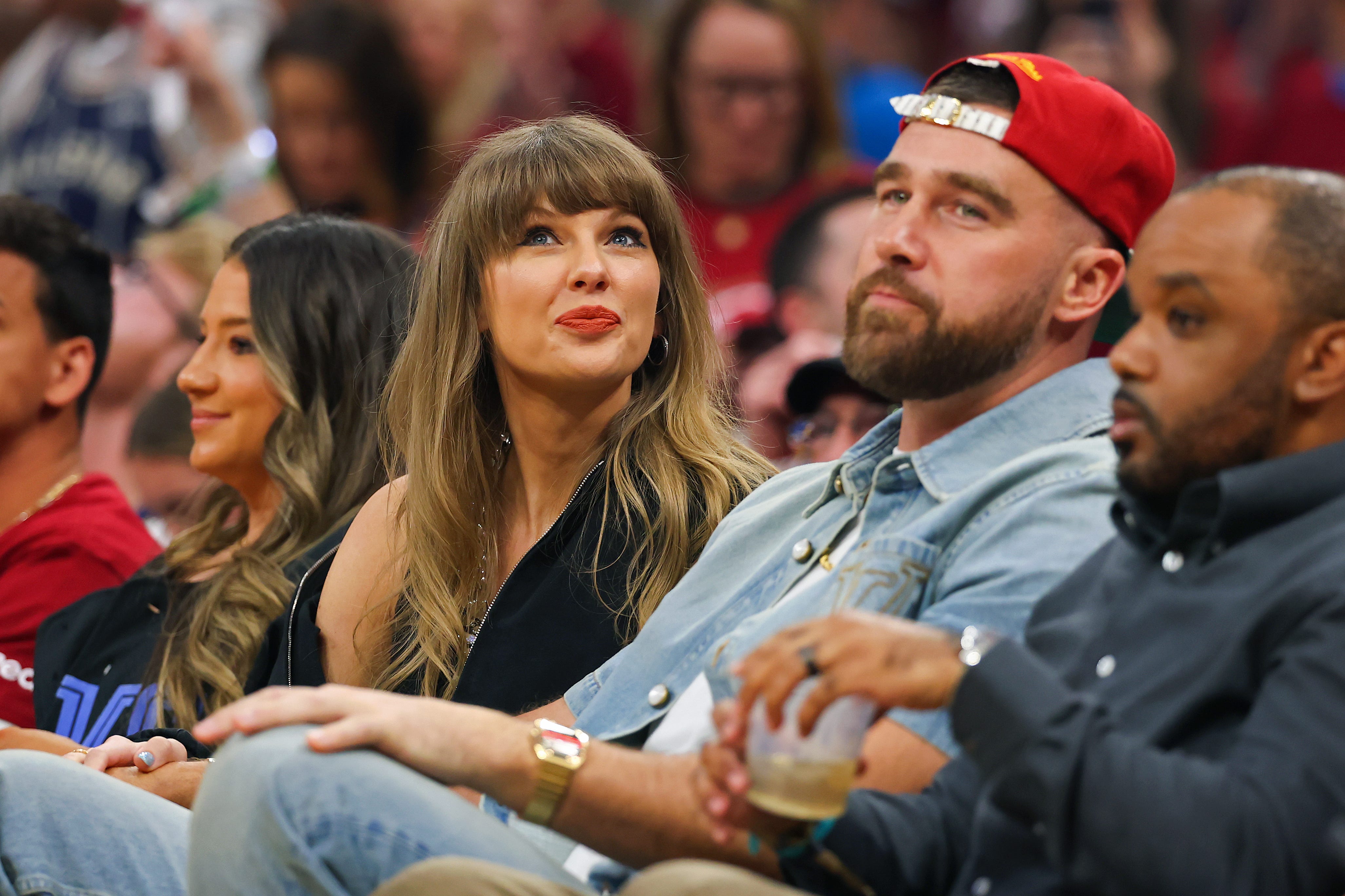 Travis Kelce chugs beer as he sits courtside with Taylor Swift at ...