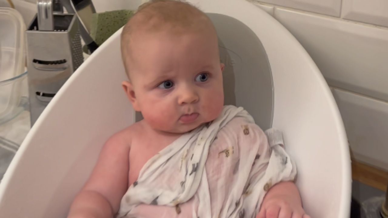 Little boy isn't too thrilled about bath time in the kitchen sink