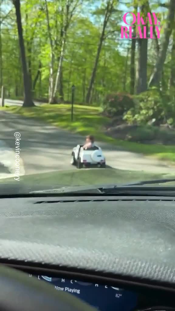 Adorable little girl drives her toy car chaotically while dad films