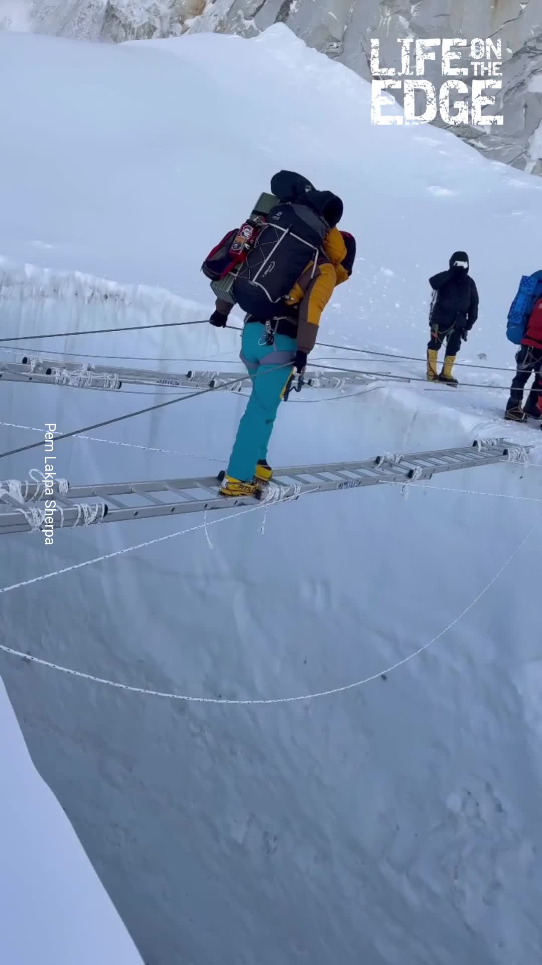 Climber carefully crosses ladder during Everest expedition