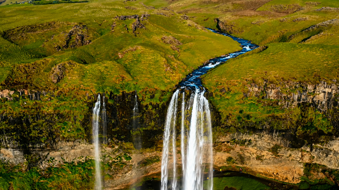Hidden waterfall flowing through endless green hills