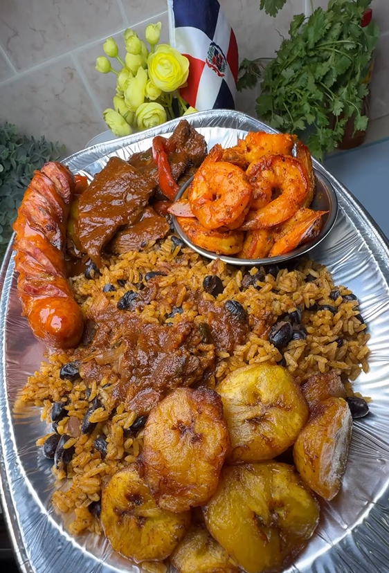 Stewed beef and grilled shrimp dinner with rice, beans, and sweet plantains