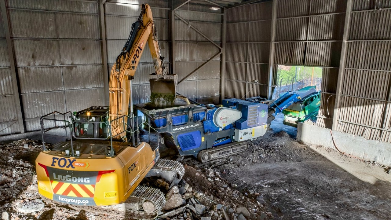 Heavy excavator operating industrial concrete crushing equipment