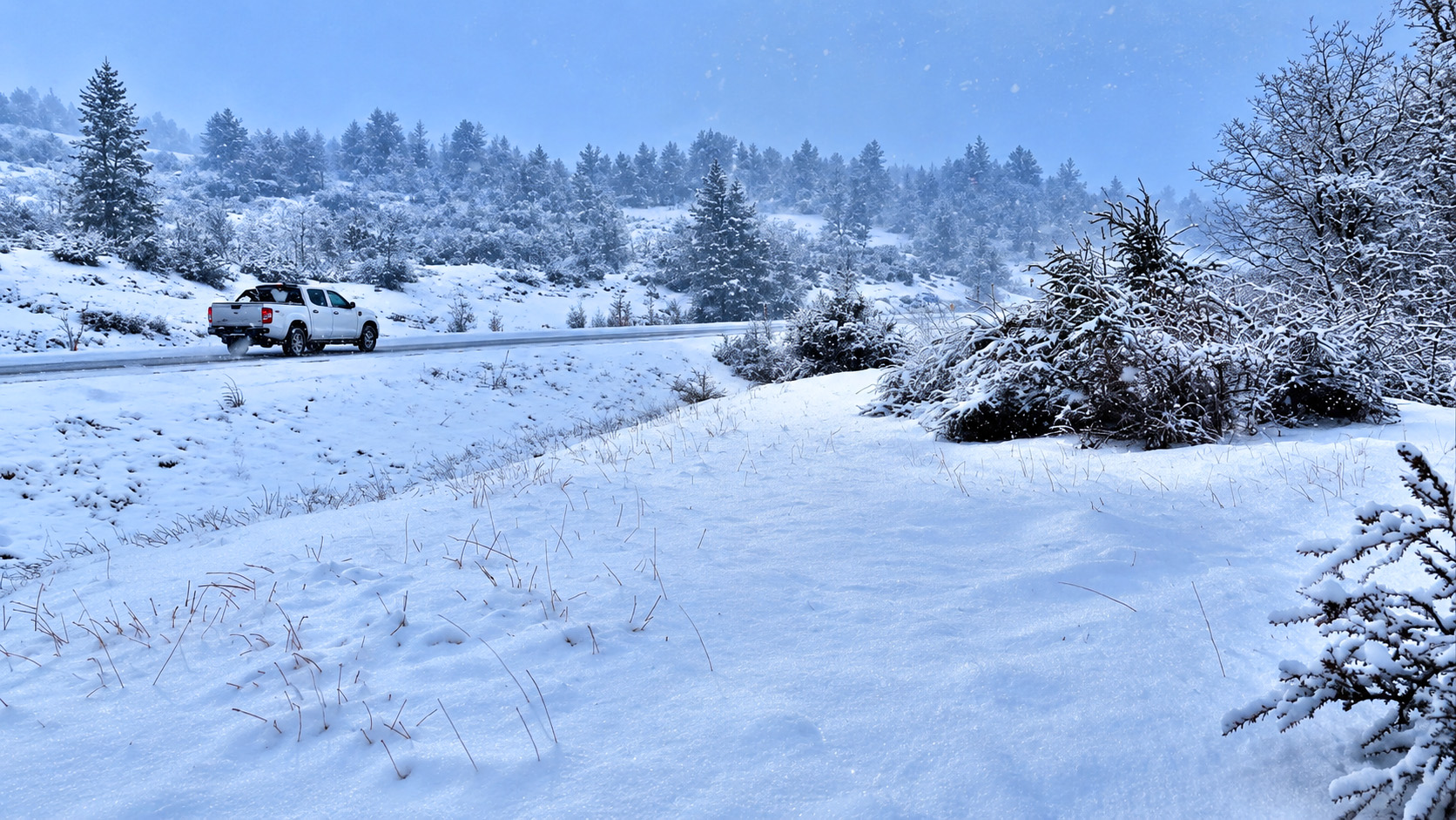 A remote mountain road lost in a heavy snowstorm