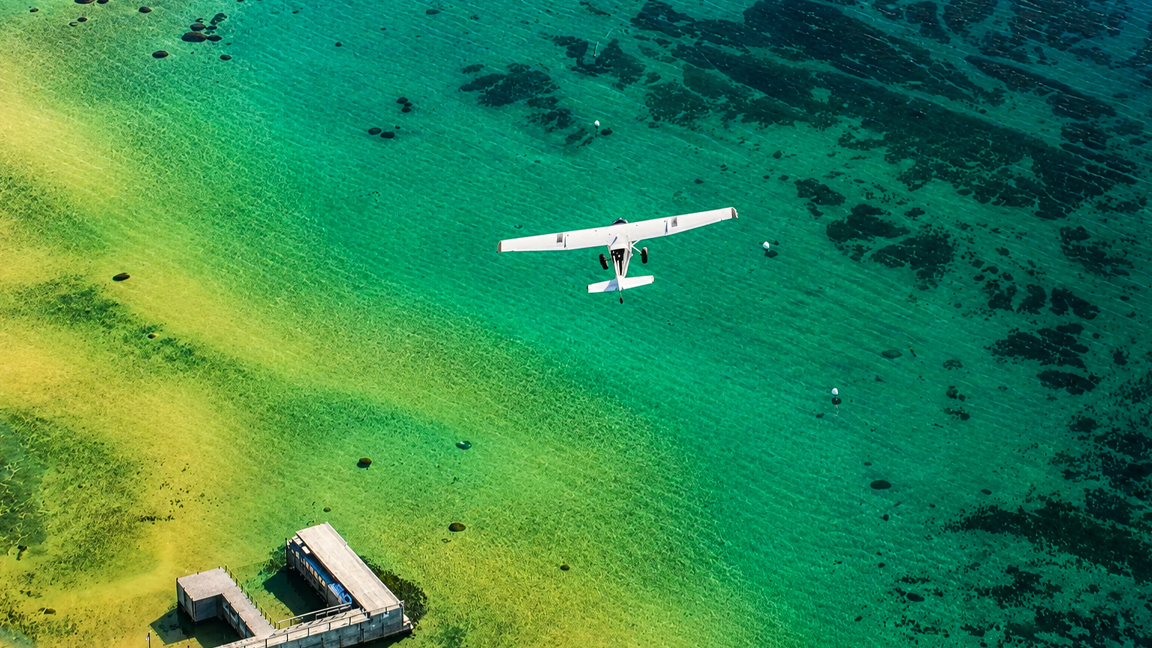 Piccolo aereo in volo sopra acque tropicali cristalline