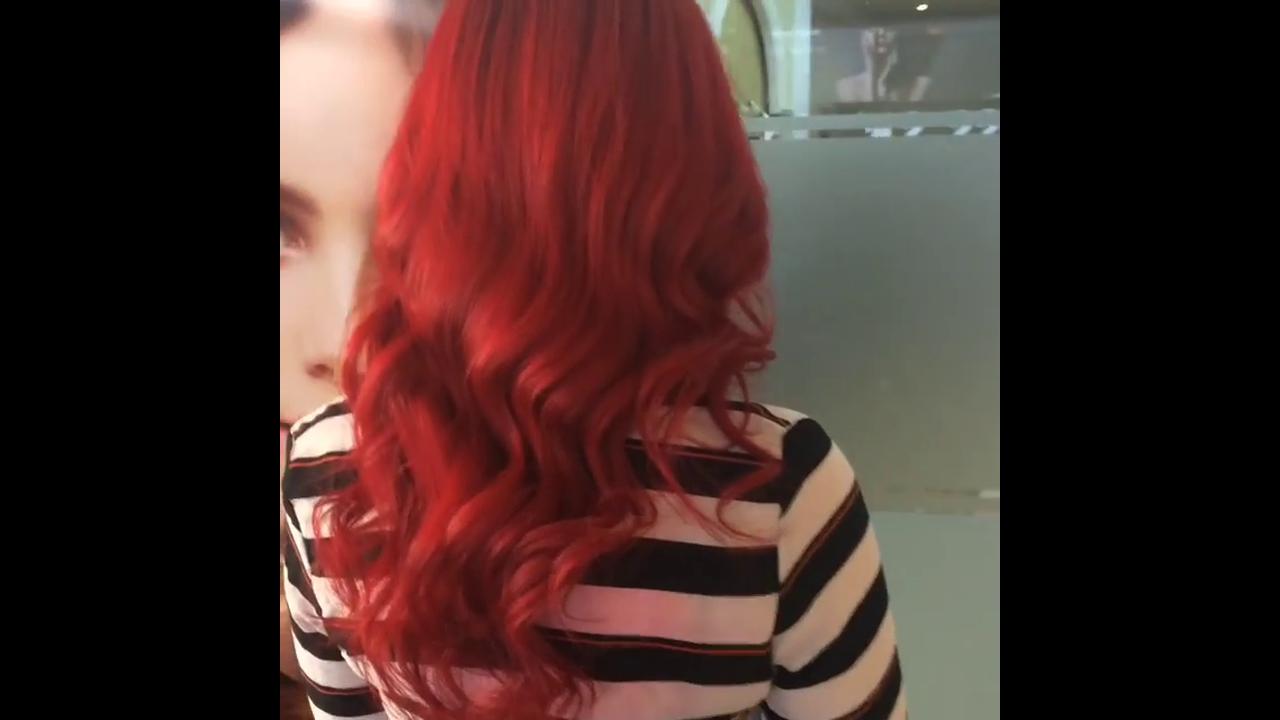 Styling long bright red hair with loose curling motion producing smooth ...