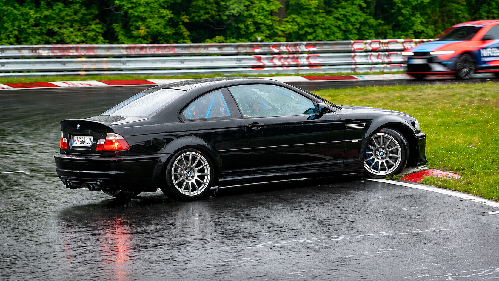 BMW spins out after losing control on a wet track