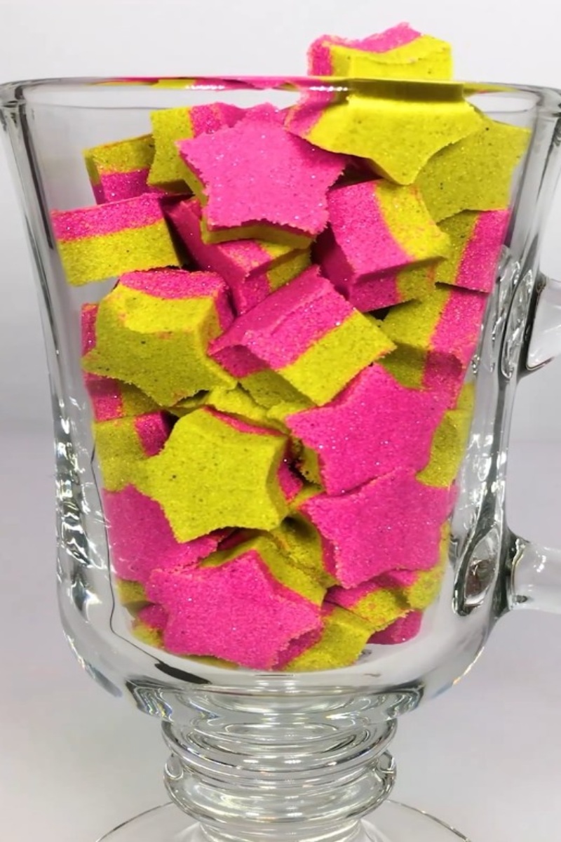 Colorful kinetic sand star shapes in glass cup