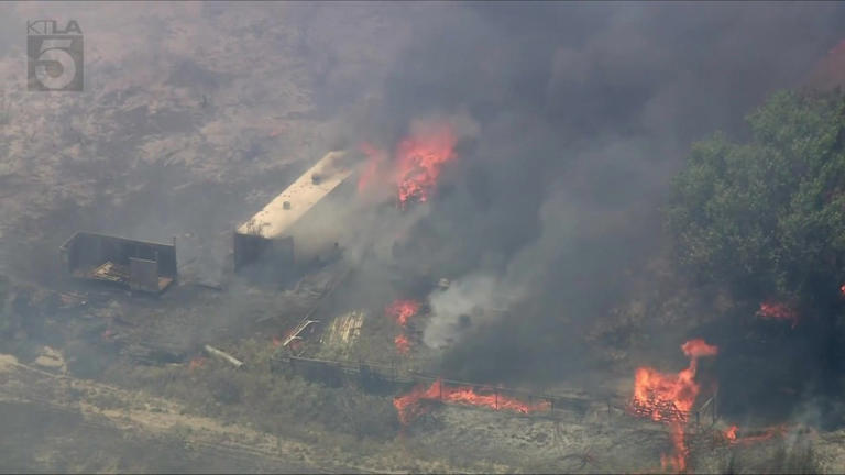 Crews battle brush fire burning structures in Riverside County