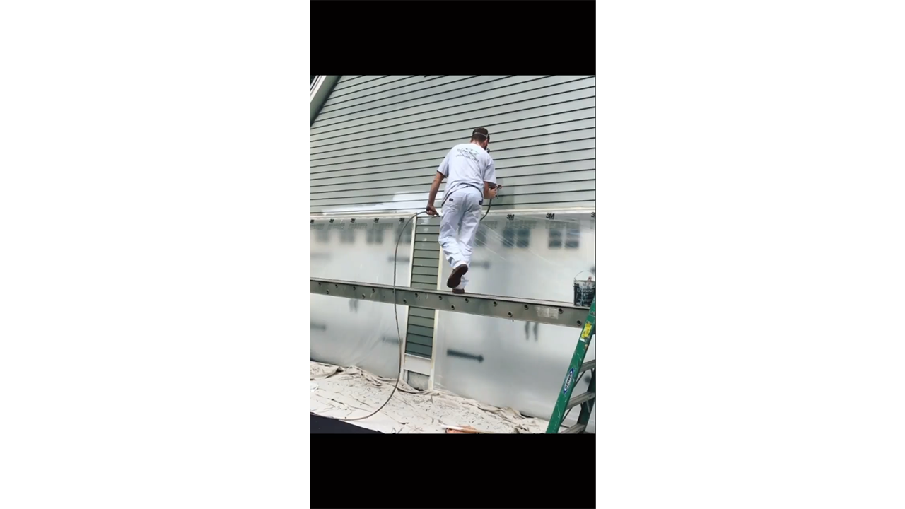 Careful exterior wall painting with spray gun creating modern gray ...