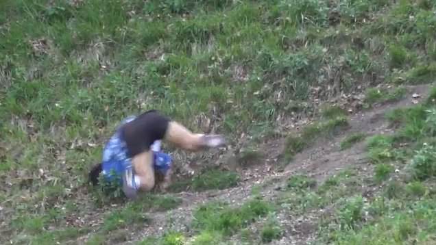 Men somersaulting down steep hill chasing a wheel of cheese looks like ...