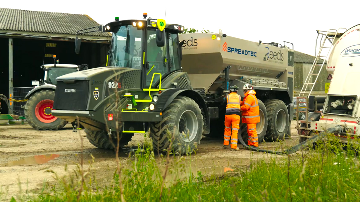 Massive spreader truck carrying huge loads through deep mud