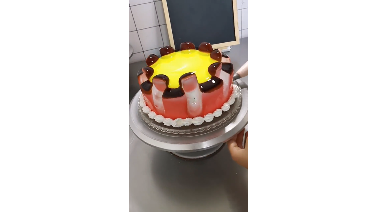 Decorating glossy red jelly cake with chocolate drip and bright yellow ...