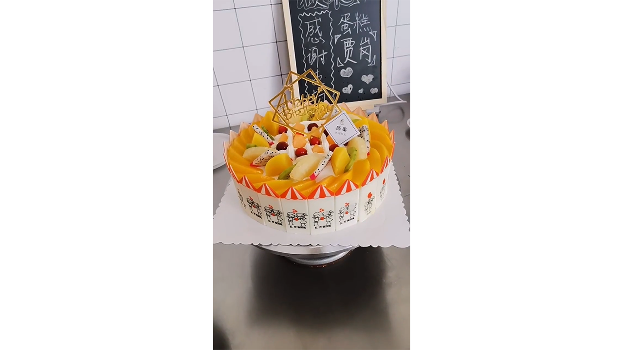 Decorating white cream cake with orange flame frosting and fresh fruit ...
