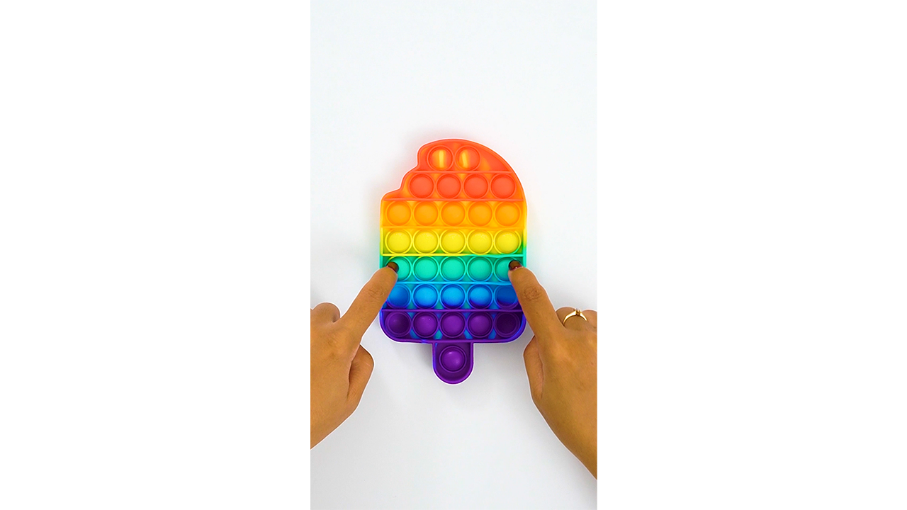 Pressing a rainbow popsicle pop it with smooth bubble texture