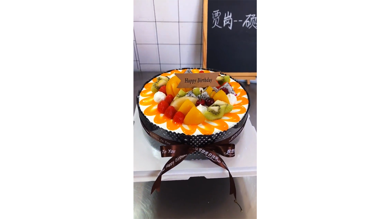 Decorating white cream cake with mango flower pattern and fresh fruit ...