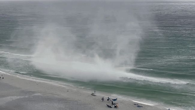 Beach umbrellas fly as waterspout comes ashore