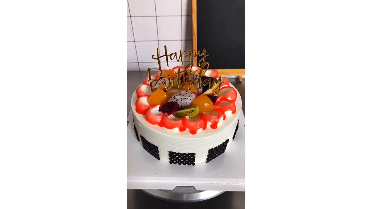 Decorating white cream cake with red strawberry glaze and fresh fruit ...