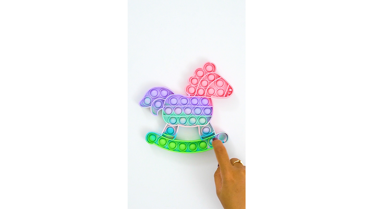 Playing with a colorful rocking horse pop it in soft rainbow colors