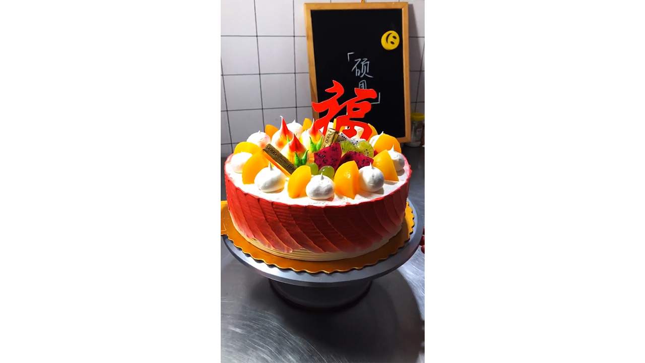 Decorating white cream cake with red longevity symbol and fresh fruit ...