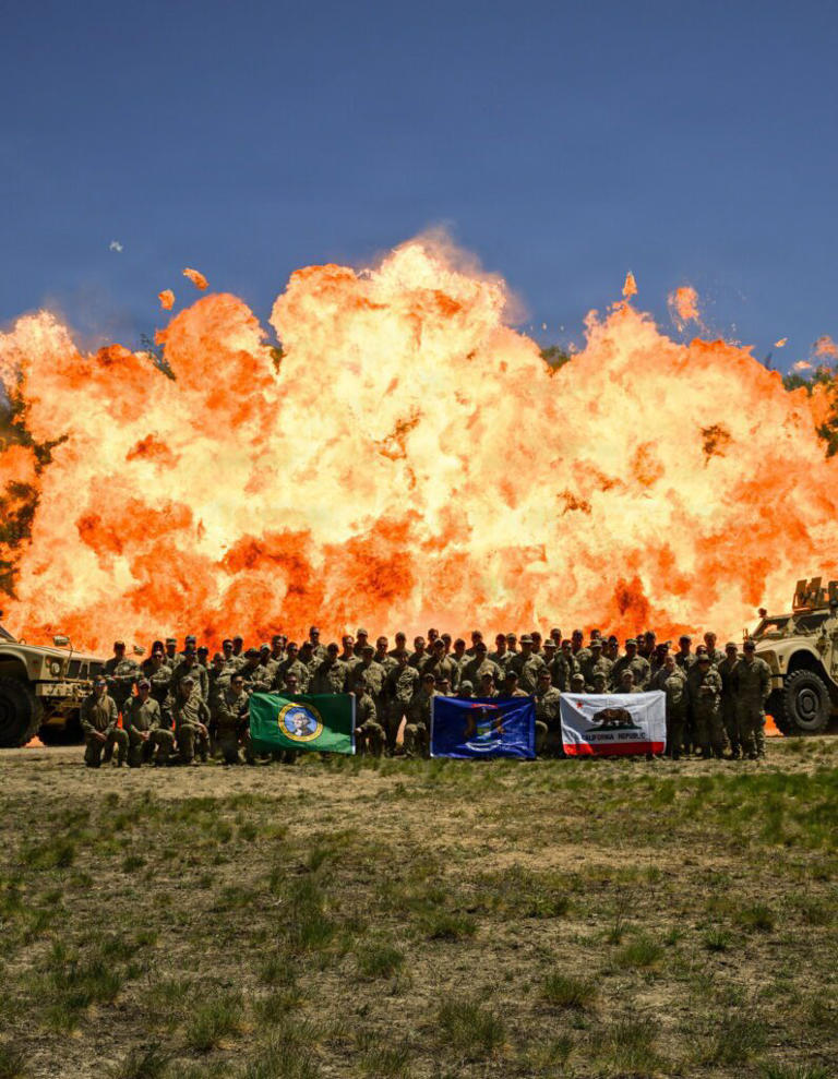 Bomb squad soldiers pose in front of huge blast during training