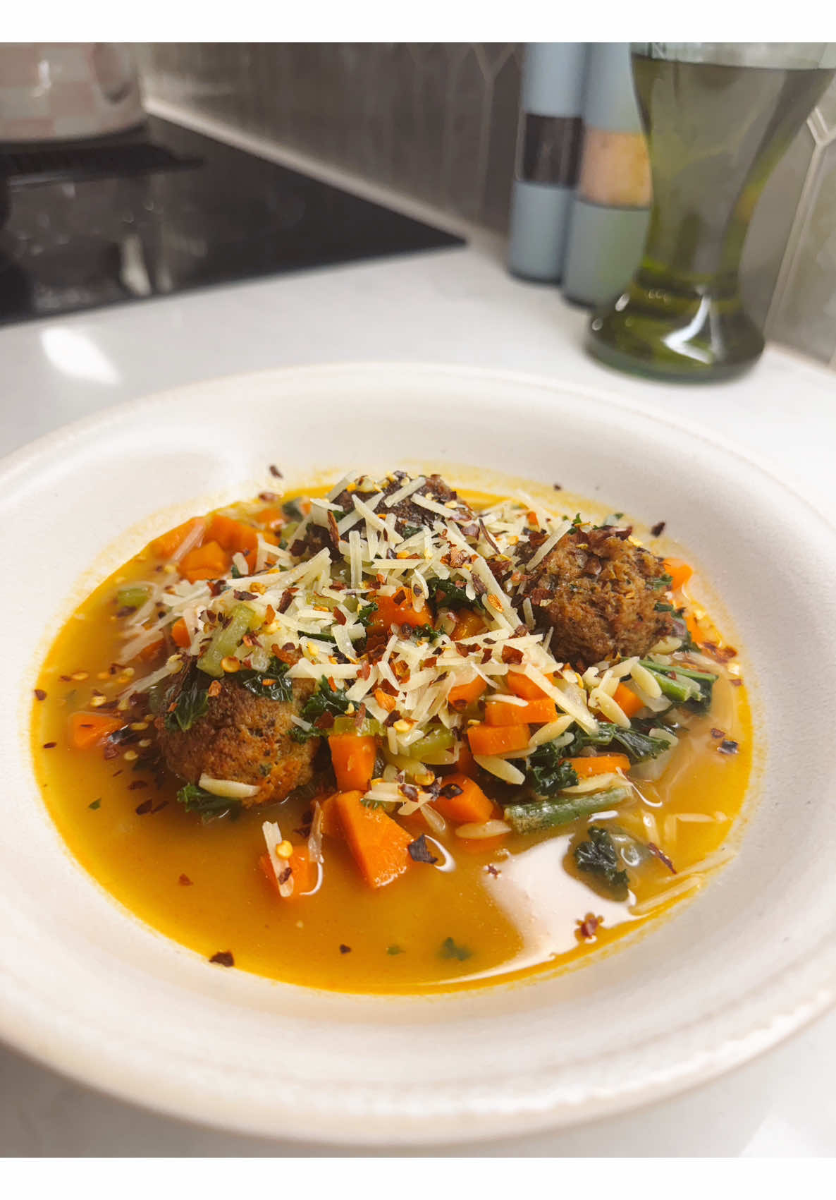 A hearty meatball and vegetable orzo soup topped with parmesan and red ...