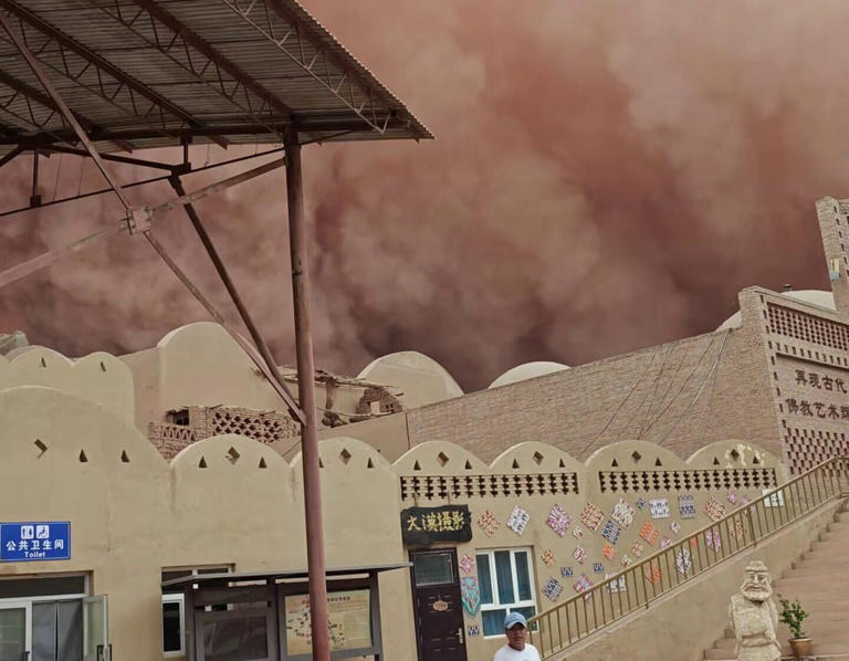 Towering sand wall engulfs tourist hotspot in eerie orange haze