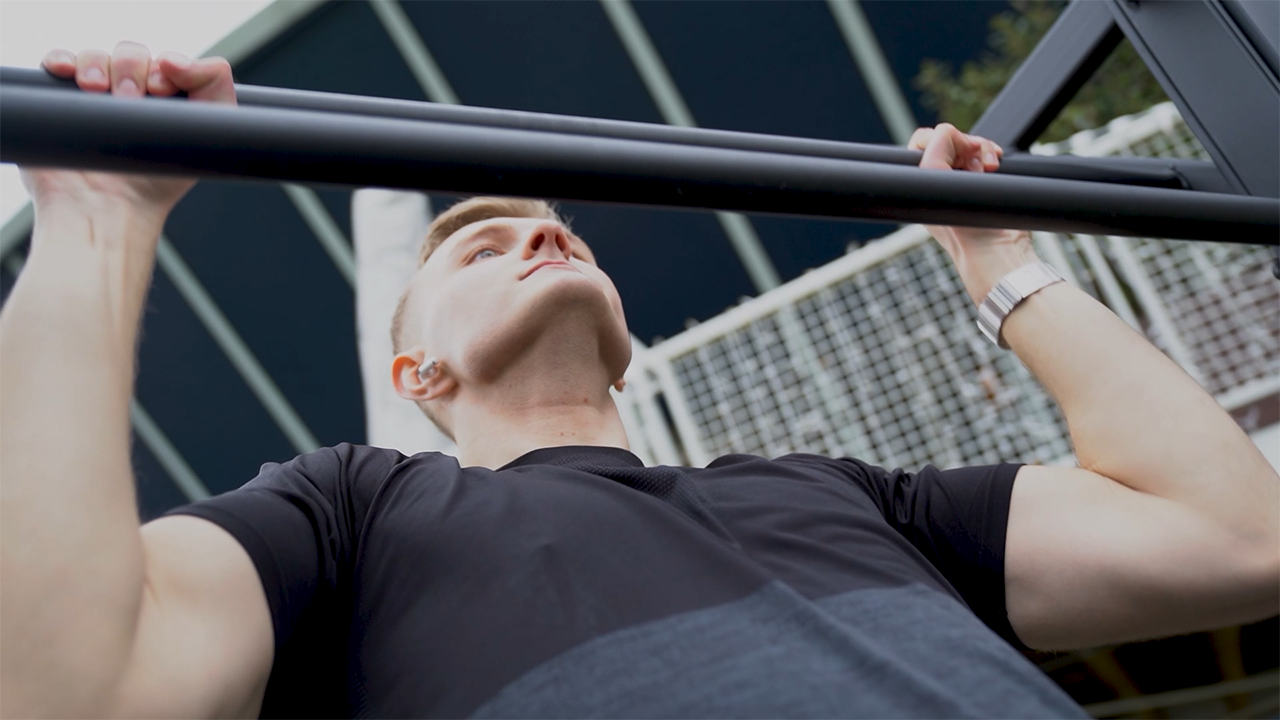 Performing powerful pull ups on outdoor fitness bars building upper ...